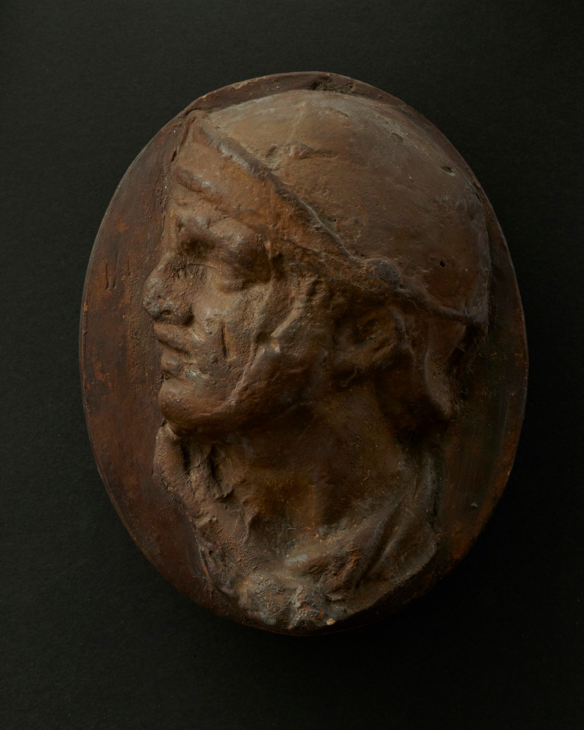 Cast of the head of Roman soldier in helmet and scarf with raised right ...